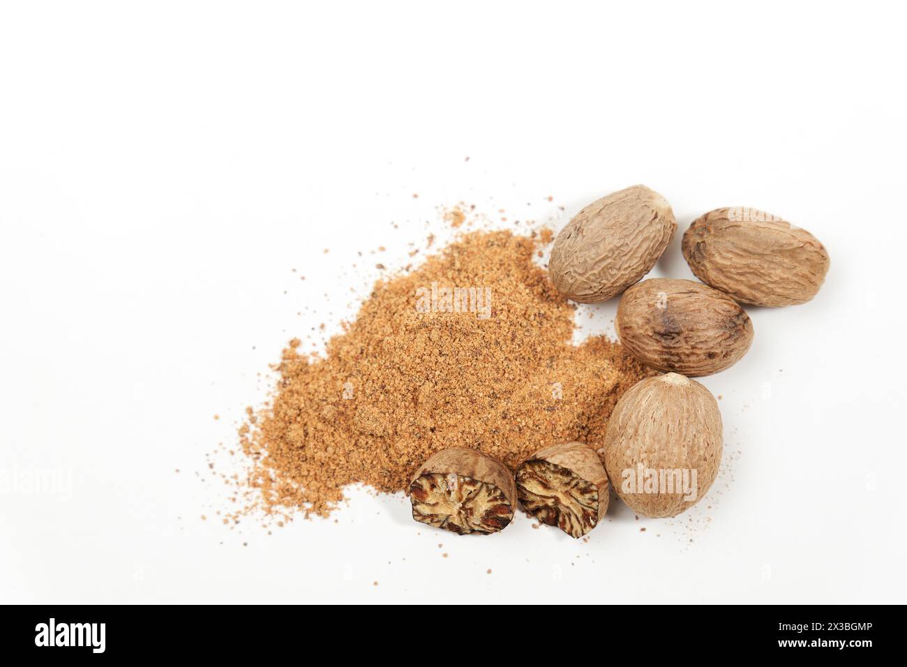 Spoon of ground nutmeg, whole and halved seeds over white background ...