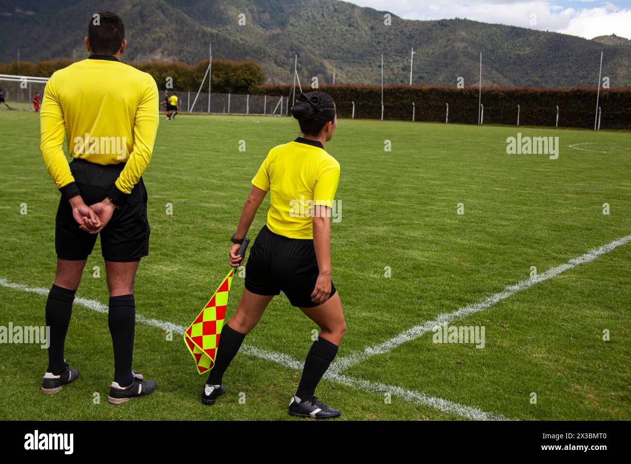 Soccer referees back to back, female assistant holds checkered flag ...