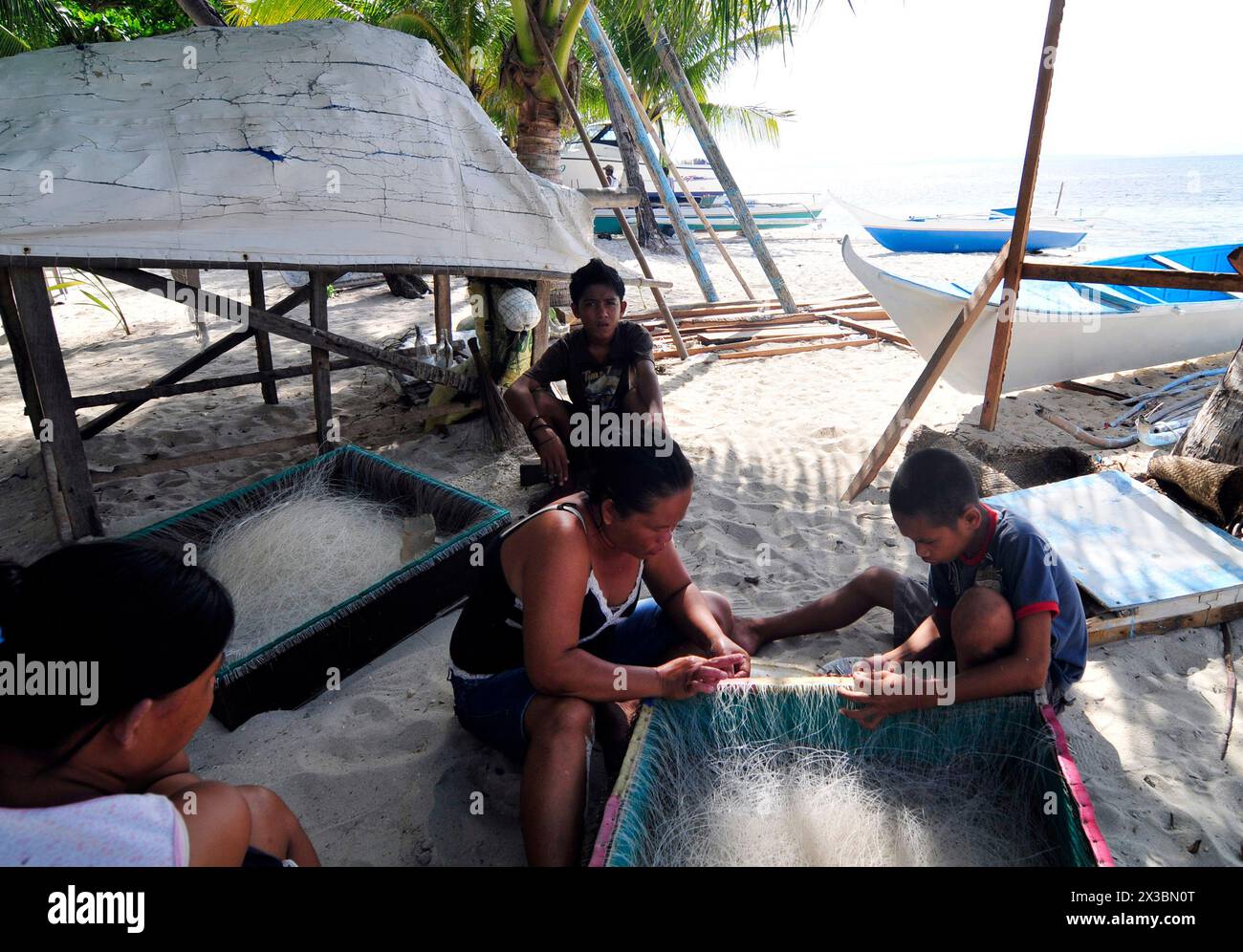 A family fixing a fishing net on the beach in Malapascua Island ...
