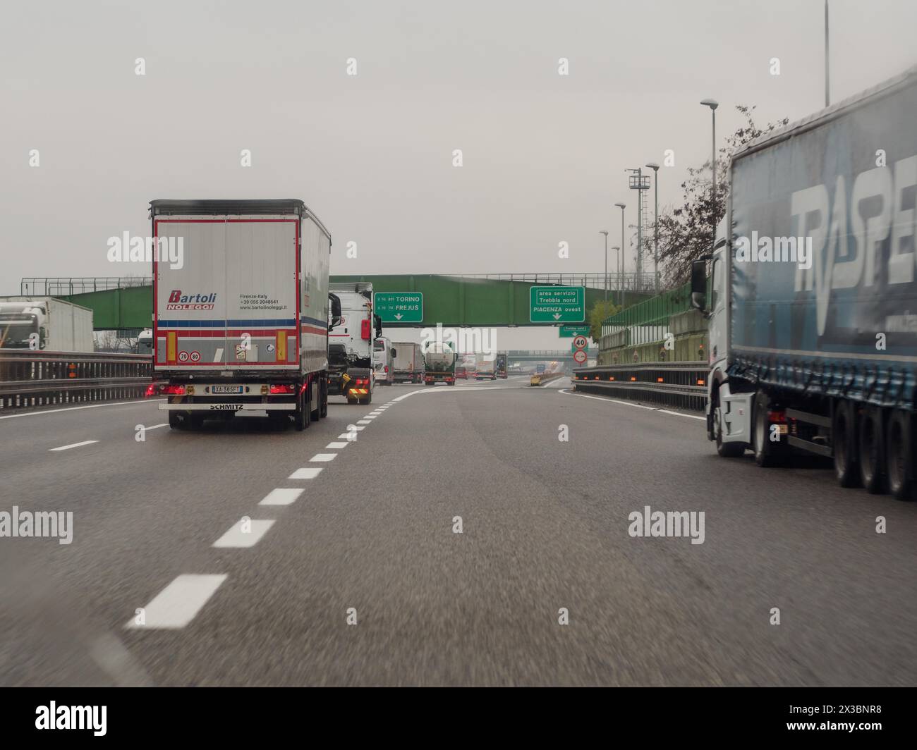 Rear view of trucks and cars driving on a highway with road signs ...
