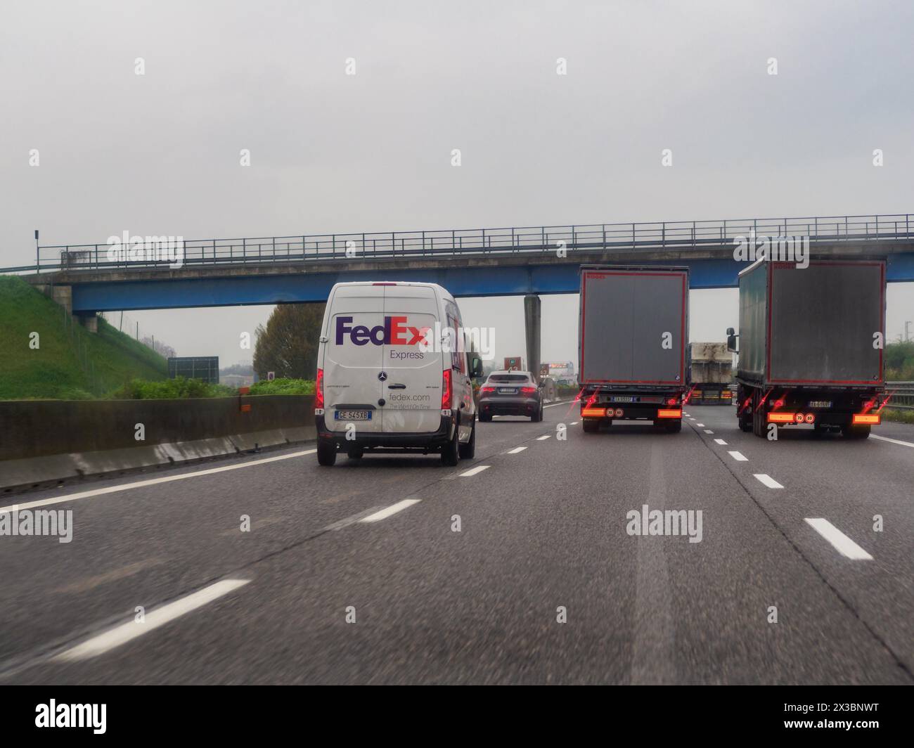 A FedEx express delivery van driving on a highway flanked by trucks, A1 ...