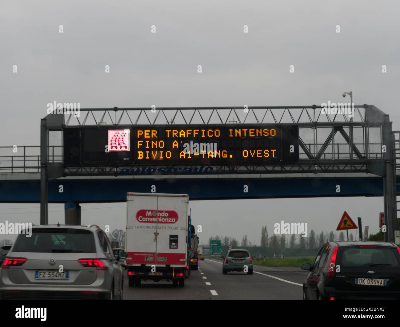Overhead traffic sign on a busy highway indicating heavy traffic ahead ...