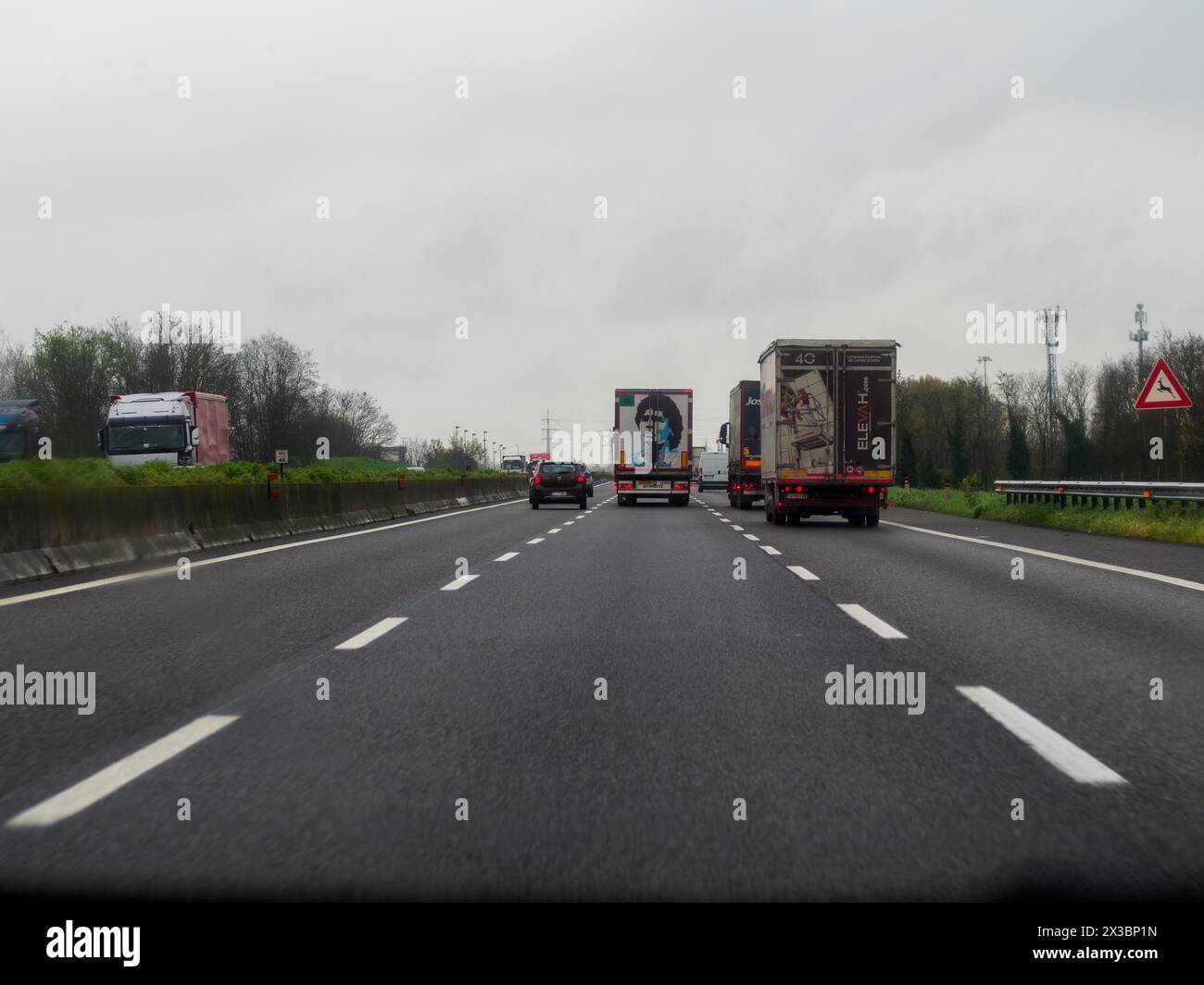 Daytime traffic on a highway with trucks and cars under an overcast sky ...