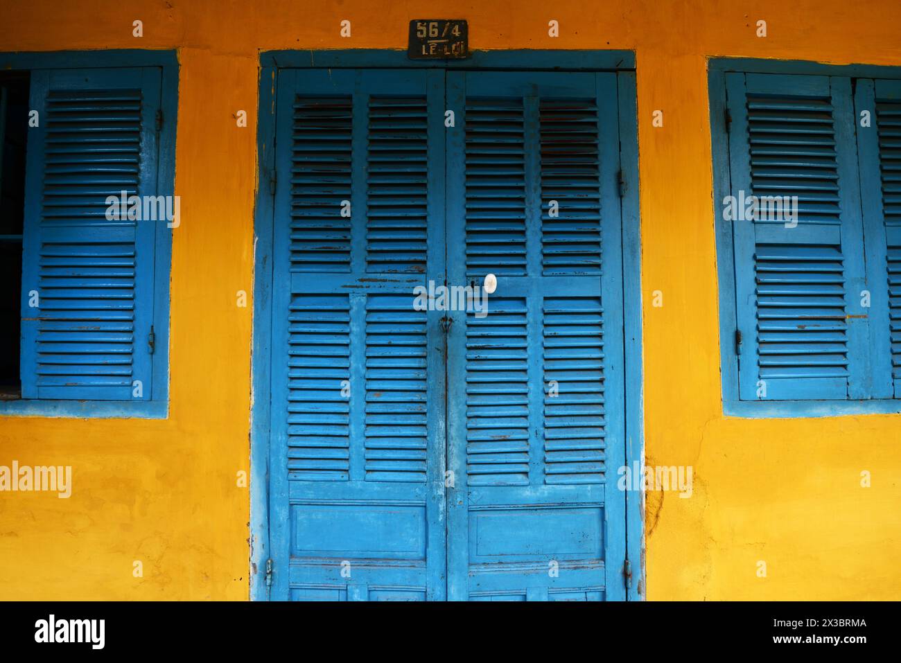 Blue wooden windows in an old yellow building. Old city of Hoi An ...