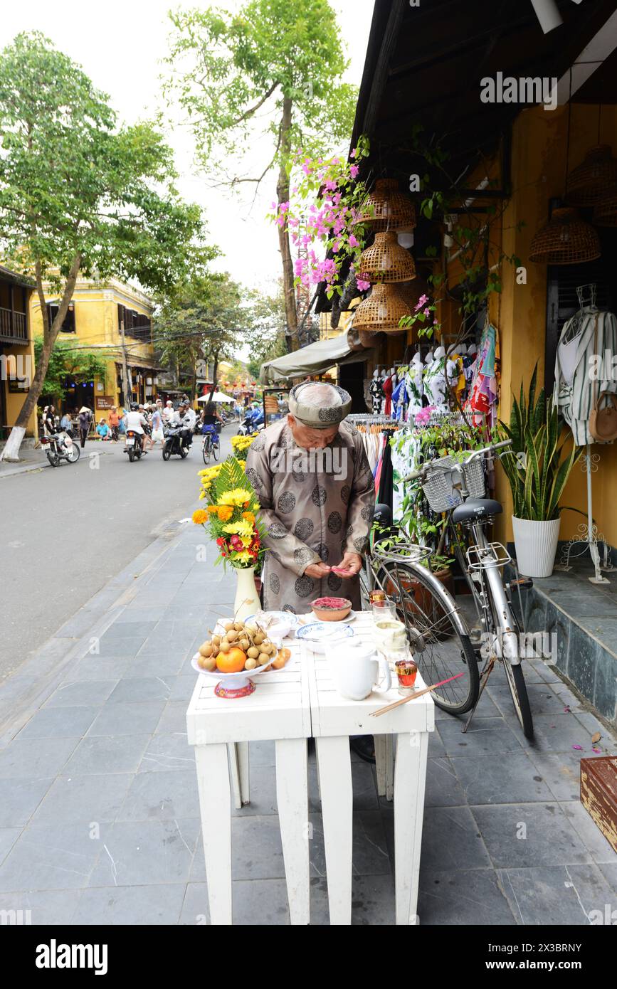 A traditionally dressed Vietnamese man preparing a ceremony outside a ...