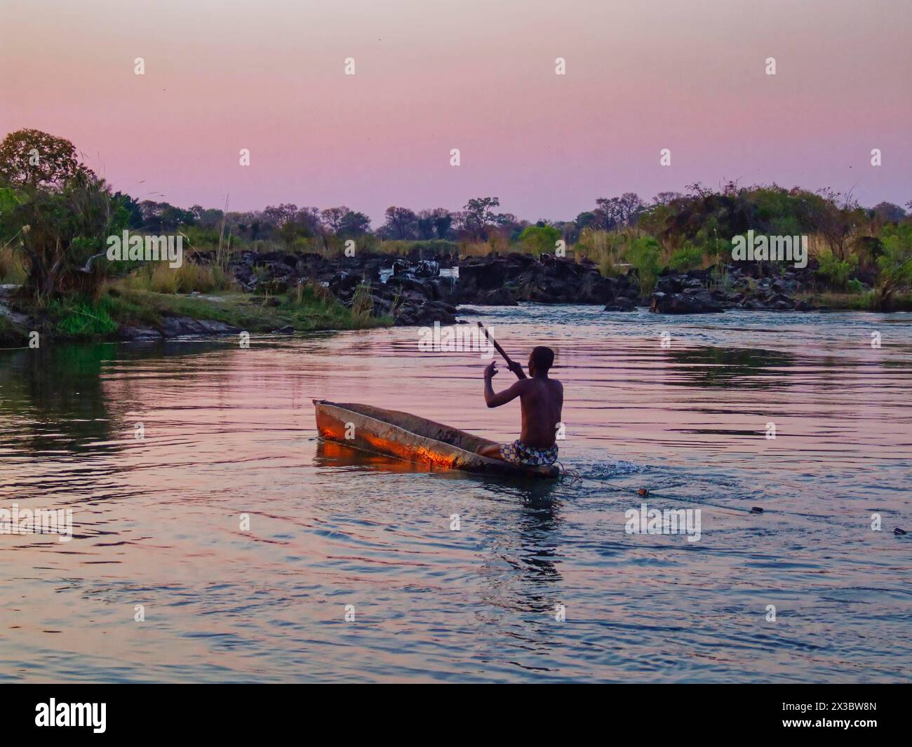 A Kavango fisherman pulls a net through a side arm of the Okavango ...