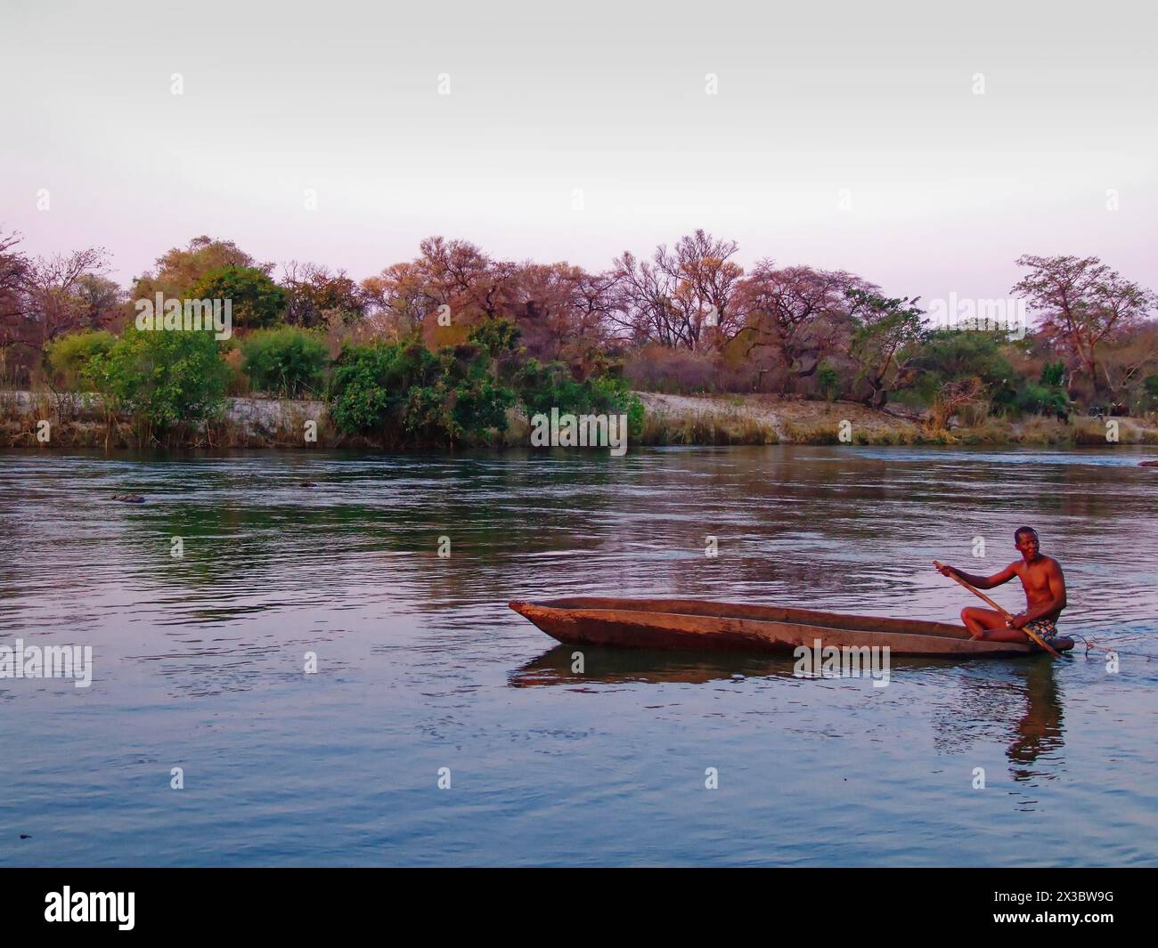 A Kavango fisherman pulls a net through a side arm of the Okavango ...