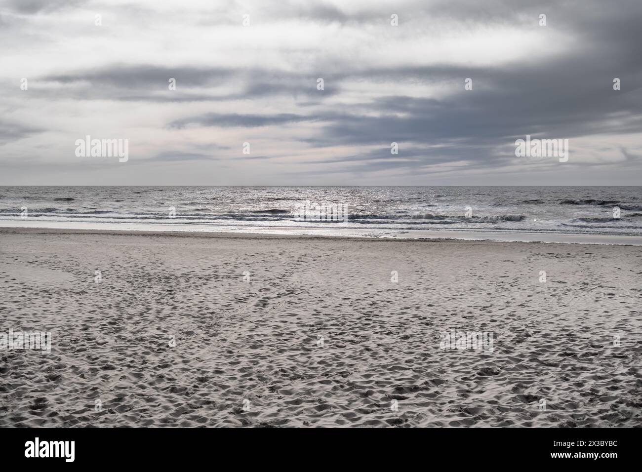 An empty beach in the Netherlands with the calm sea waves meeting the ...