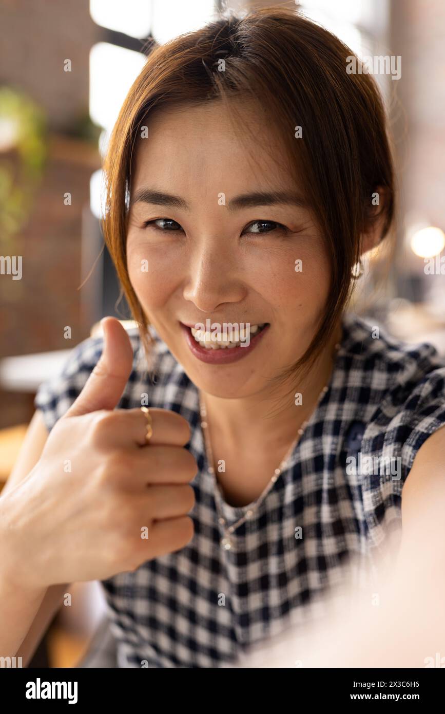 Asian Middle Aged Woman In Checkered Shirt Gives Thumbs Up In Modern