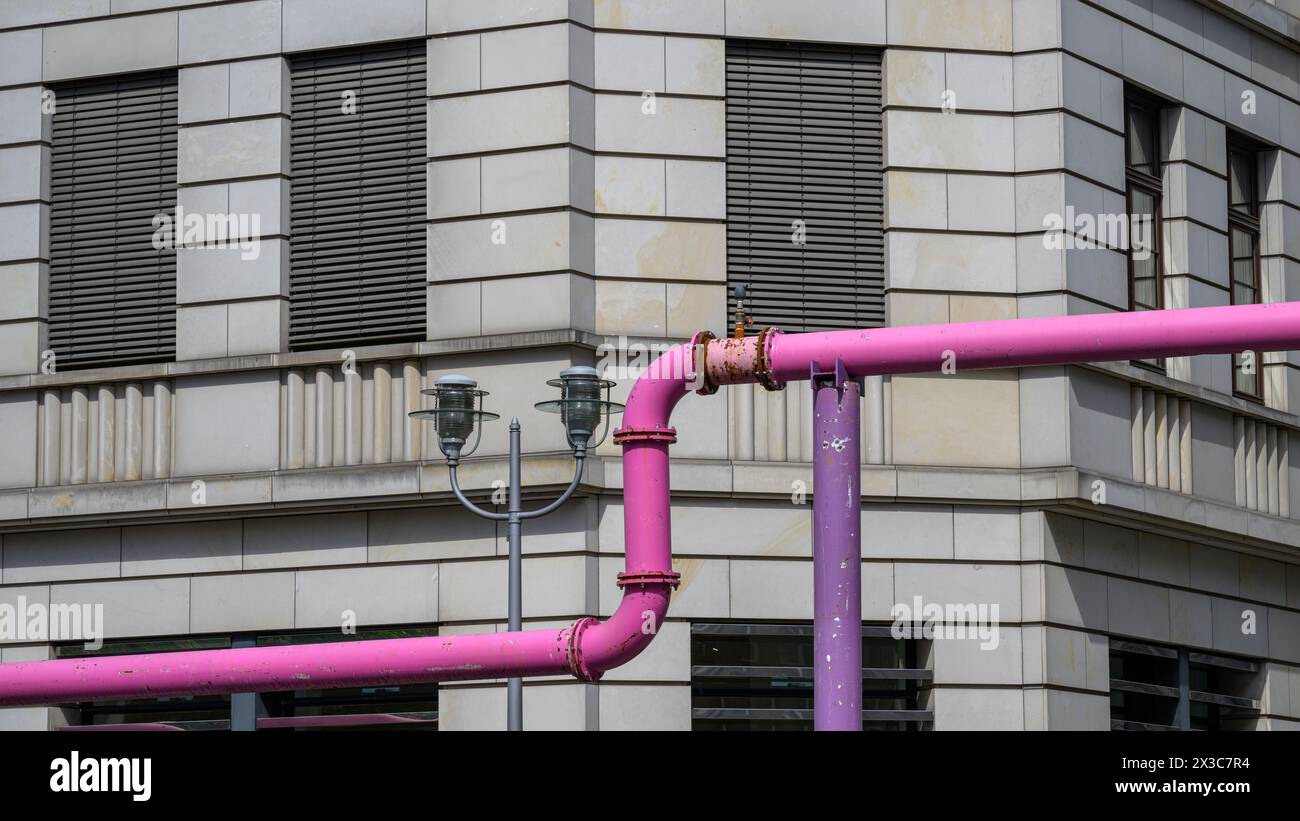 A pink pipe from a building site in front of a grey house wall Stock ...