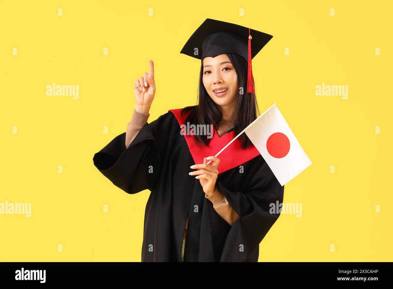 Female Asian graduate with flag of Japan pointing at something on ...
