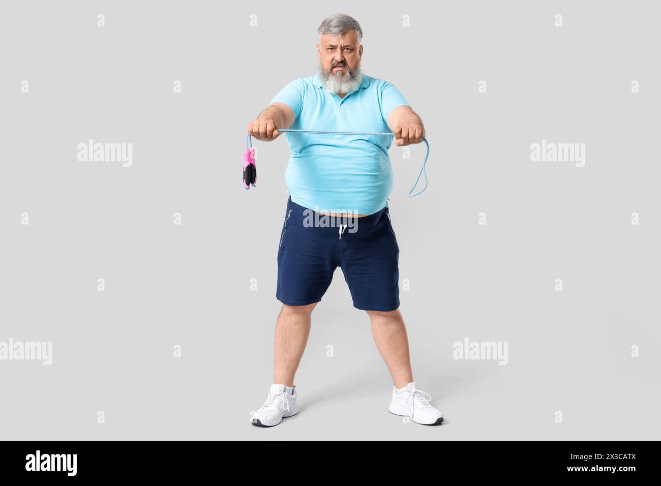 Overweight mature man with jumping rope on grey background. Weight loss ...