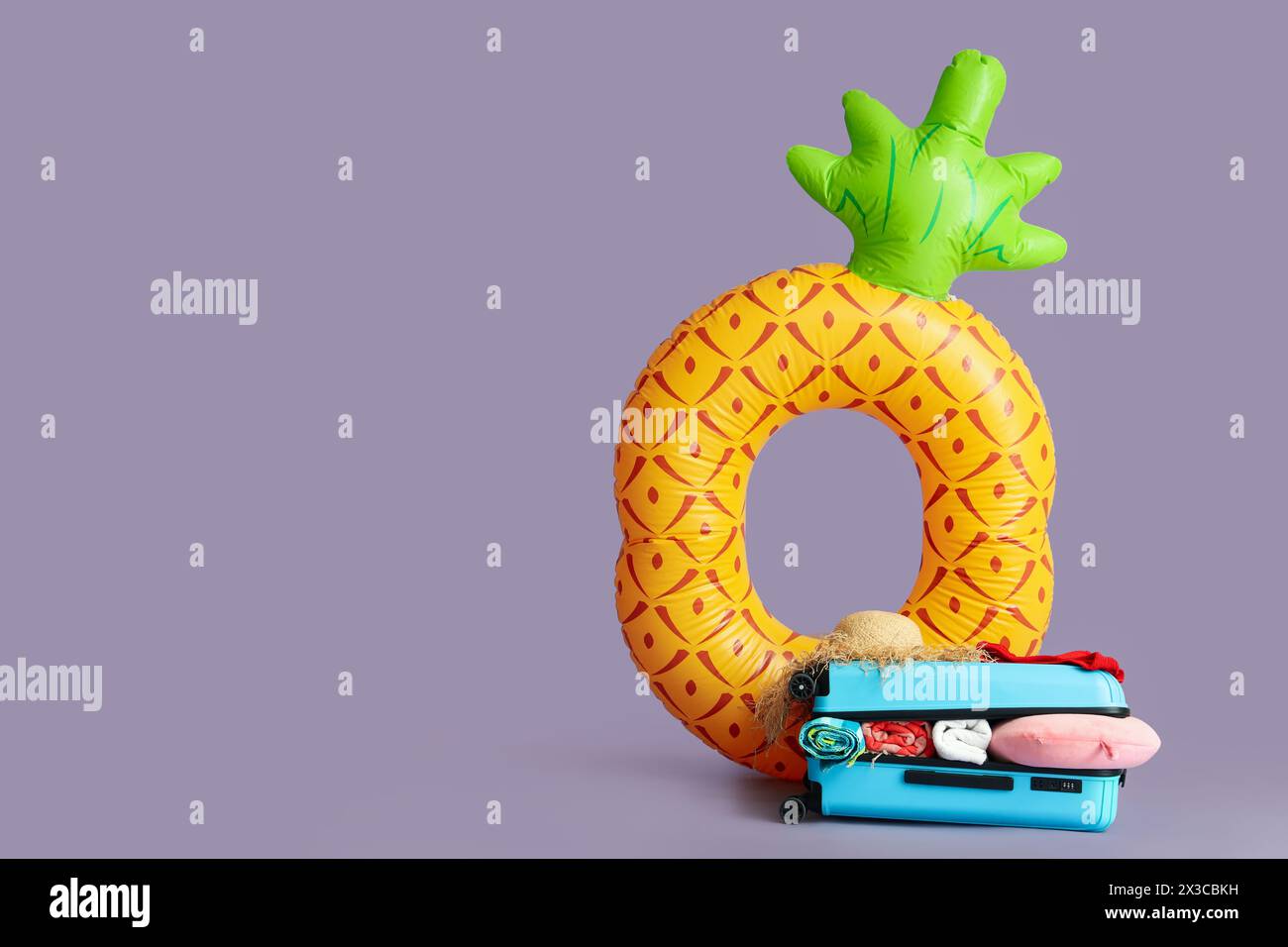 Suitcase with beach accessories and inflatable ring on color background ...