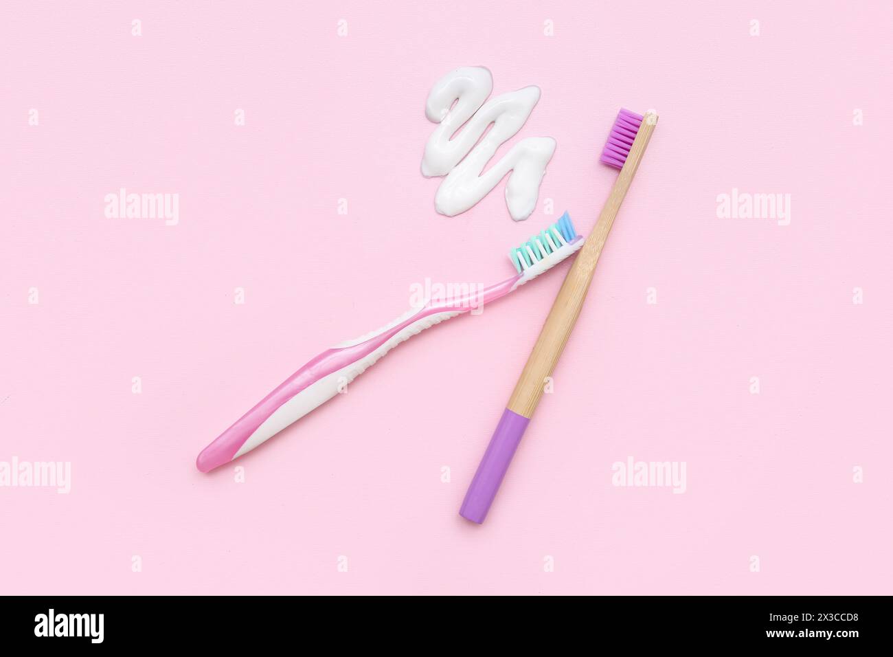 Toothbrushes with sample of toothpaste on pink background Stock Photo ...