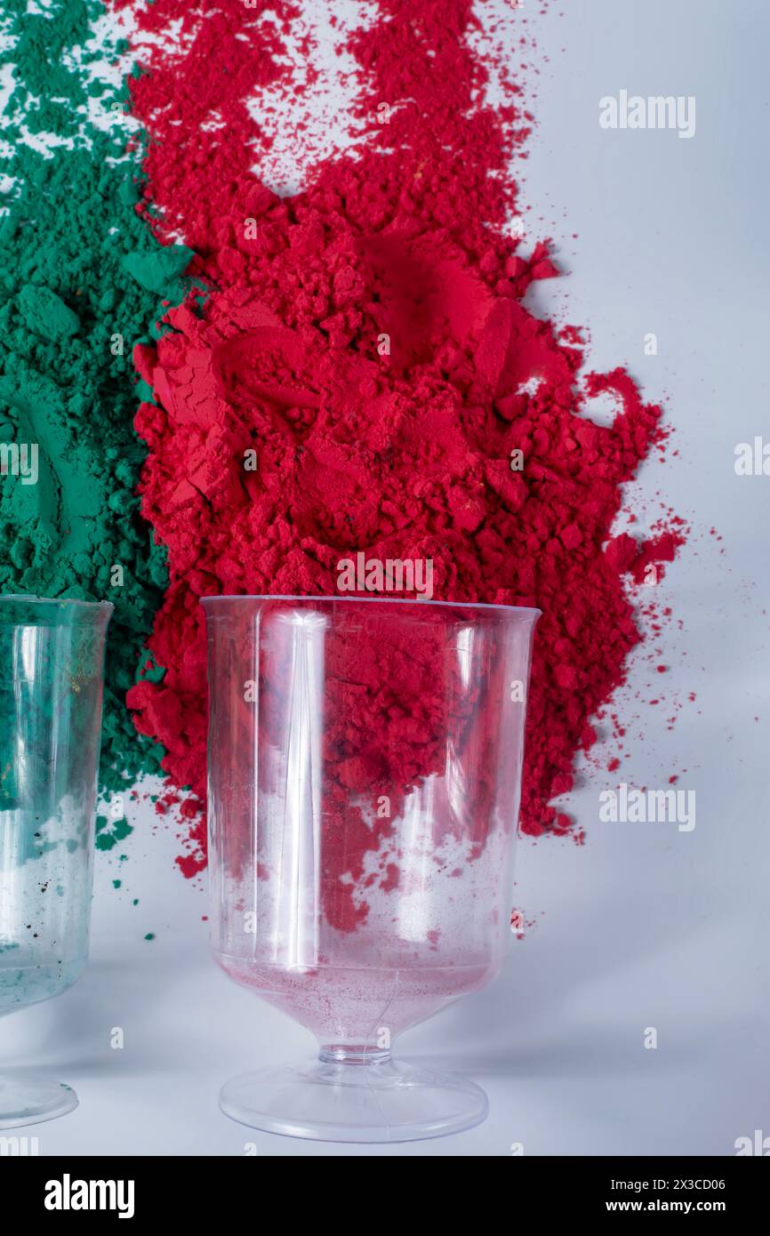 Red and green holi powder in a measuring cup on white background. Top ...