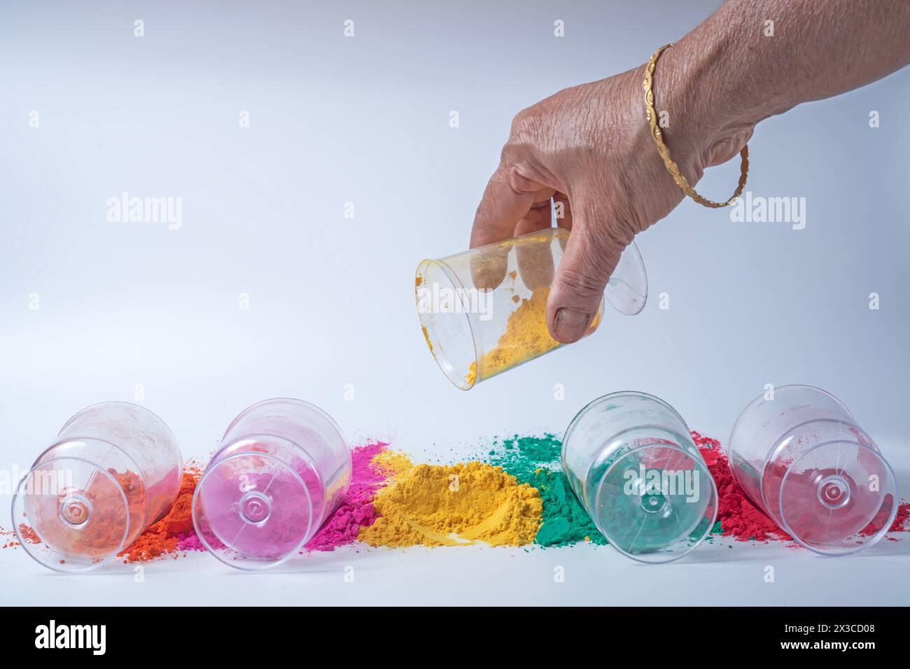 Indian woman hands pouring yellow colored holi powder into glass jars ...