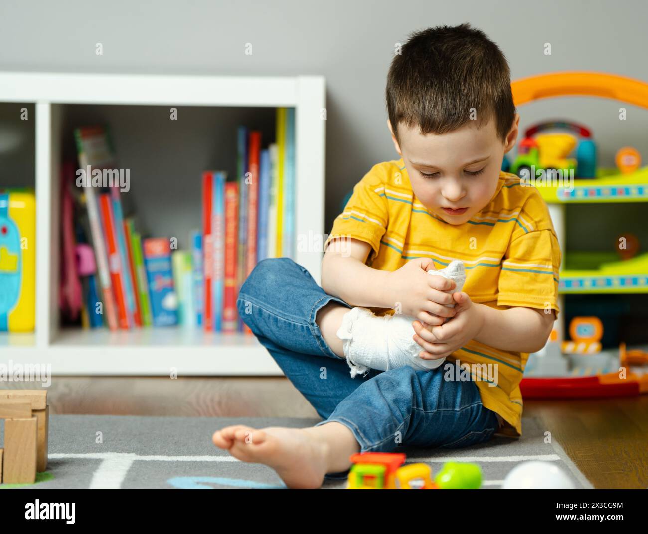 A little toddler boy holds his leg in a cast with his hands. Fracture ...