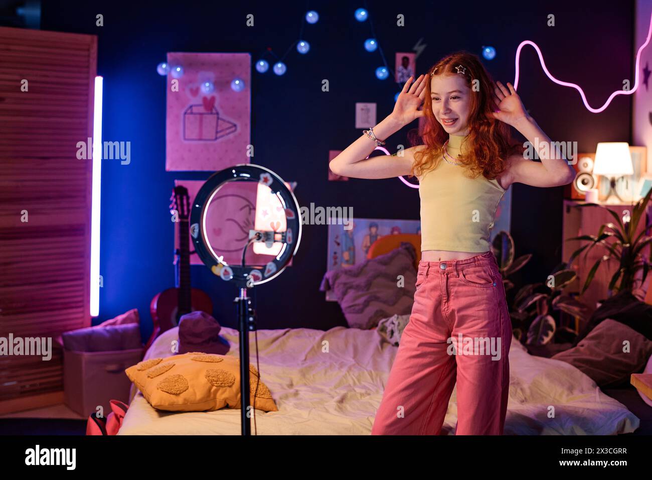 Modern teen influencer standing in neon bedroom posing for smartphone ...