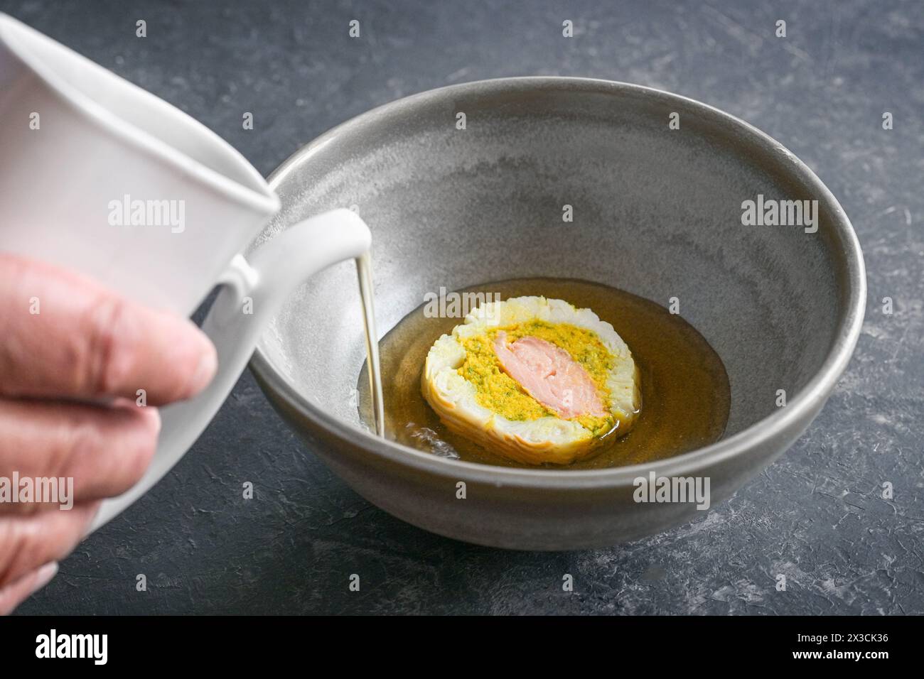 Clear broth is poured around a pate slice of three kinds of fish in a ... Clear broth is poured around a pate slice of three kinds of fish in a ...