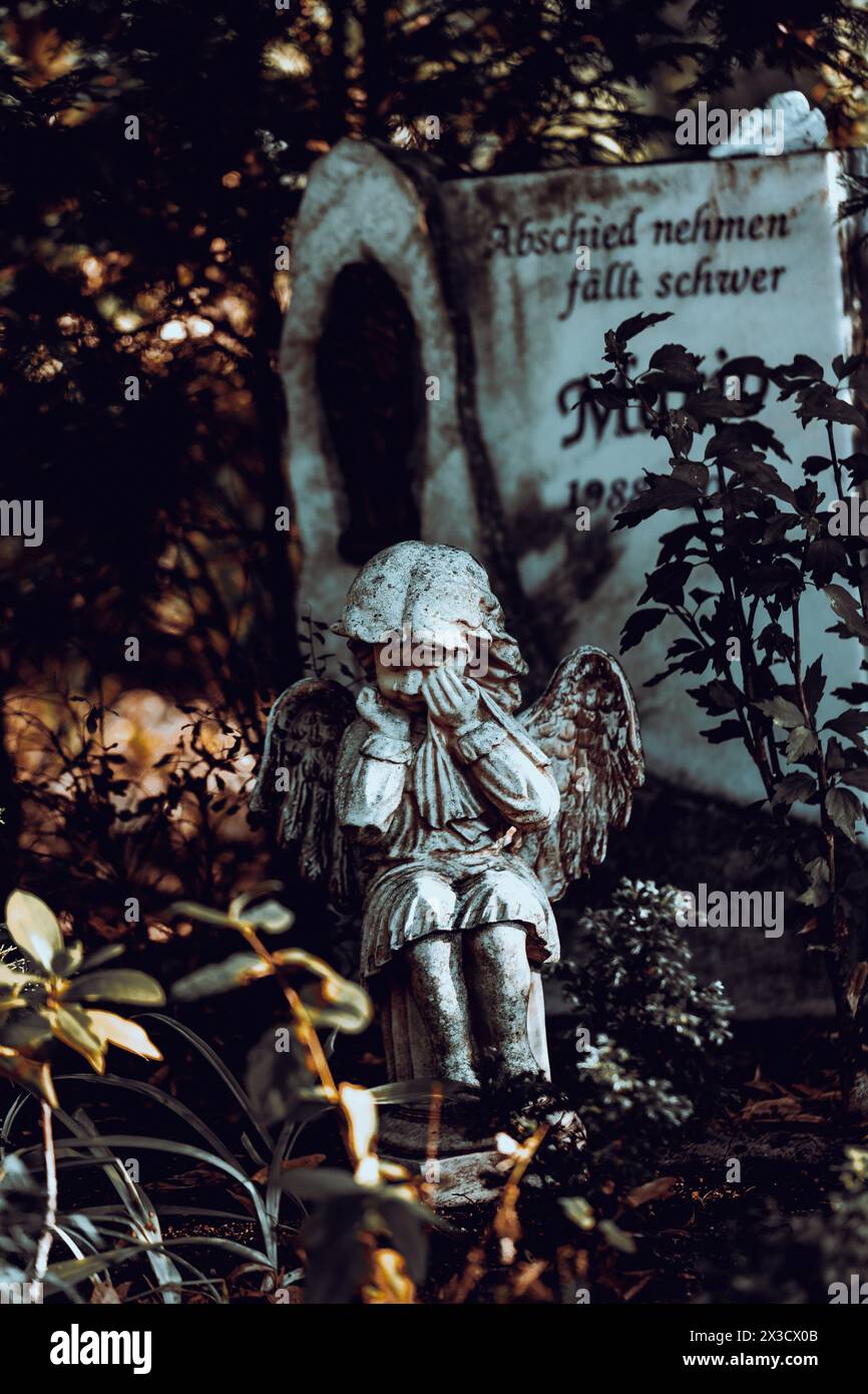 A weeping angel on a tomb, in the background a tombstone, sadness ...