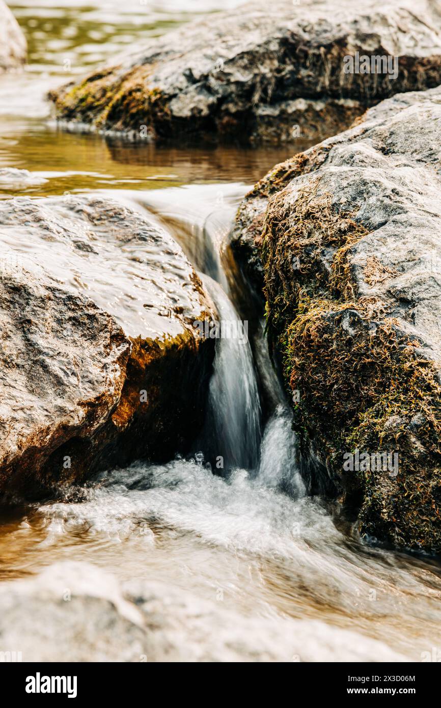 Long explosure shot of flowing river water over river rocks Stock Photo ...