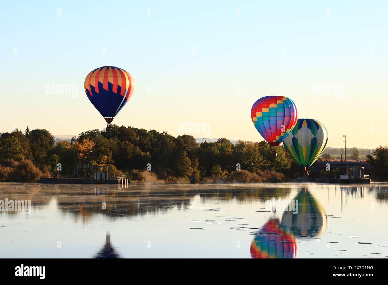 Dawn ascent of vibrant balloons over water Stock Photo - Alamy