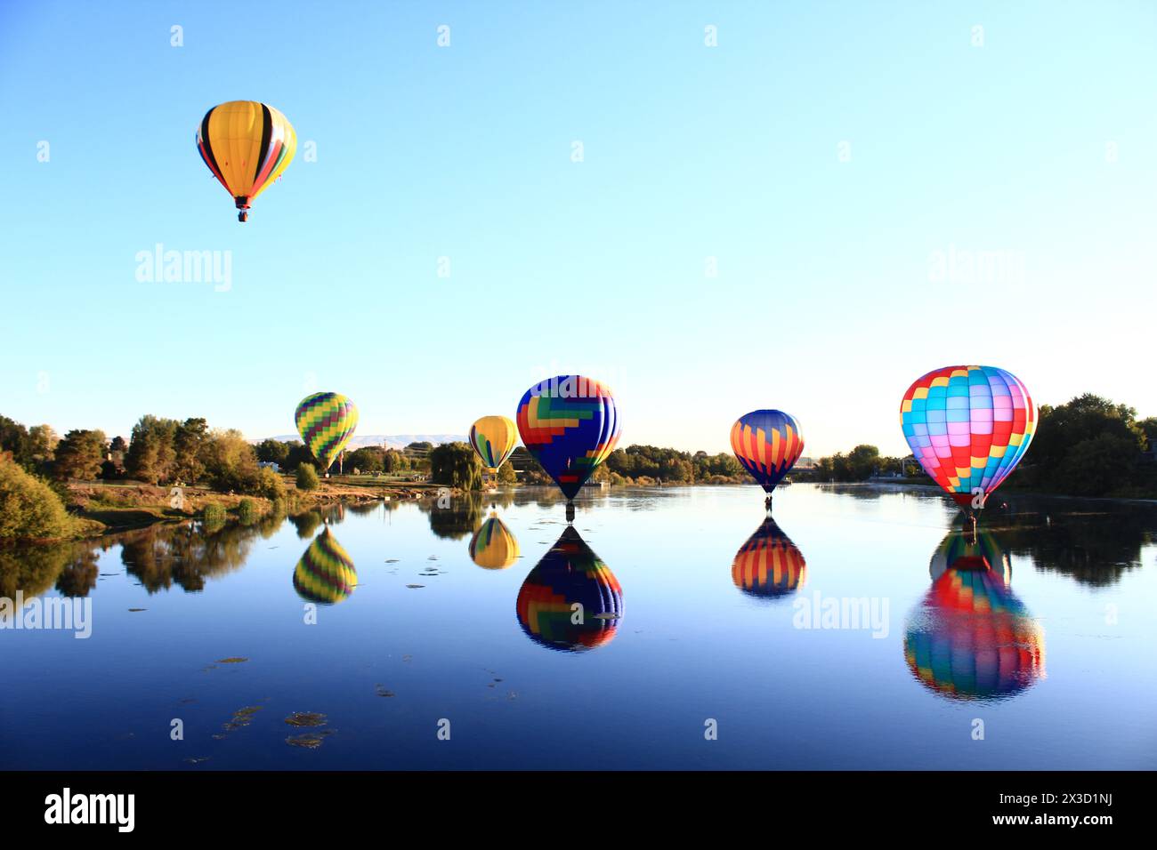 Dawn ascent of vibrant balloons over water Stock Photo - Alamy