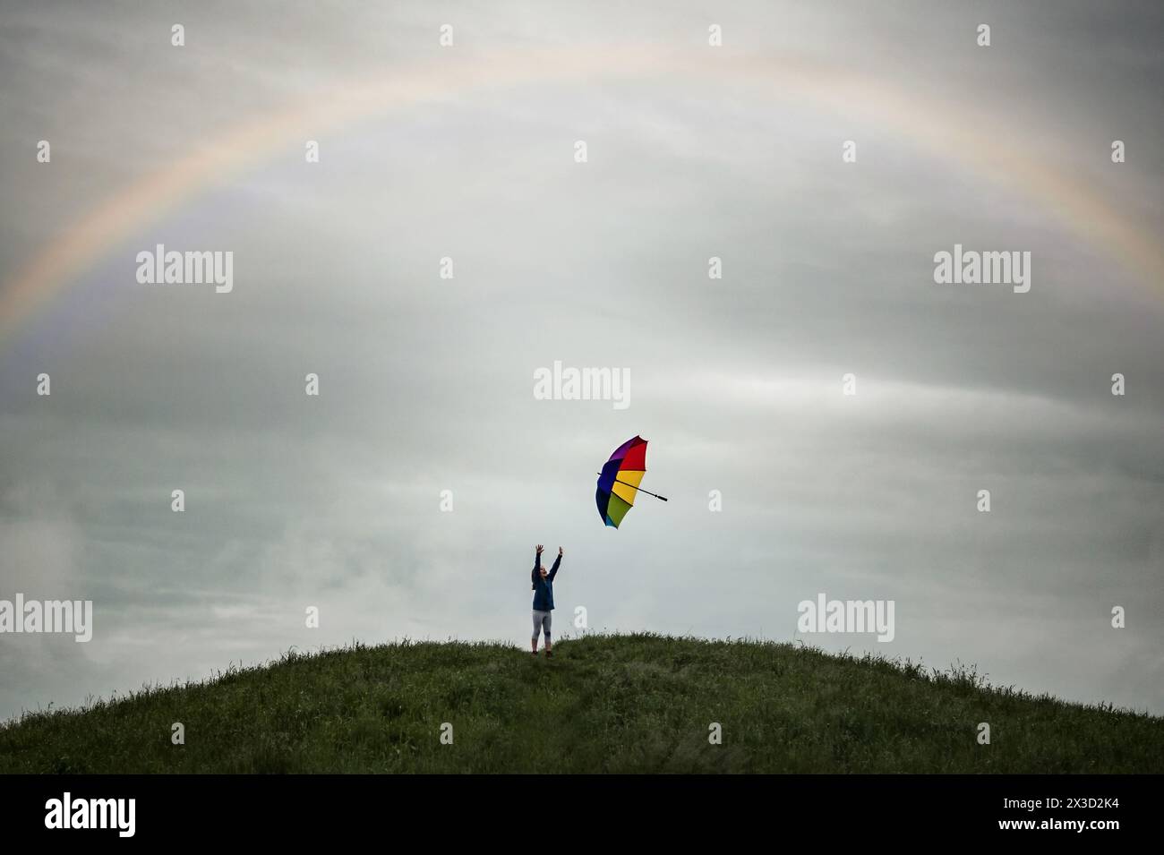 Young girl throwing rainbow umbrella in cloudy rainstorm Stock Photo ...