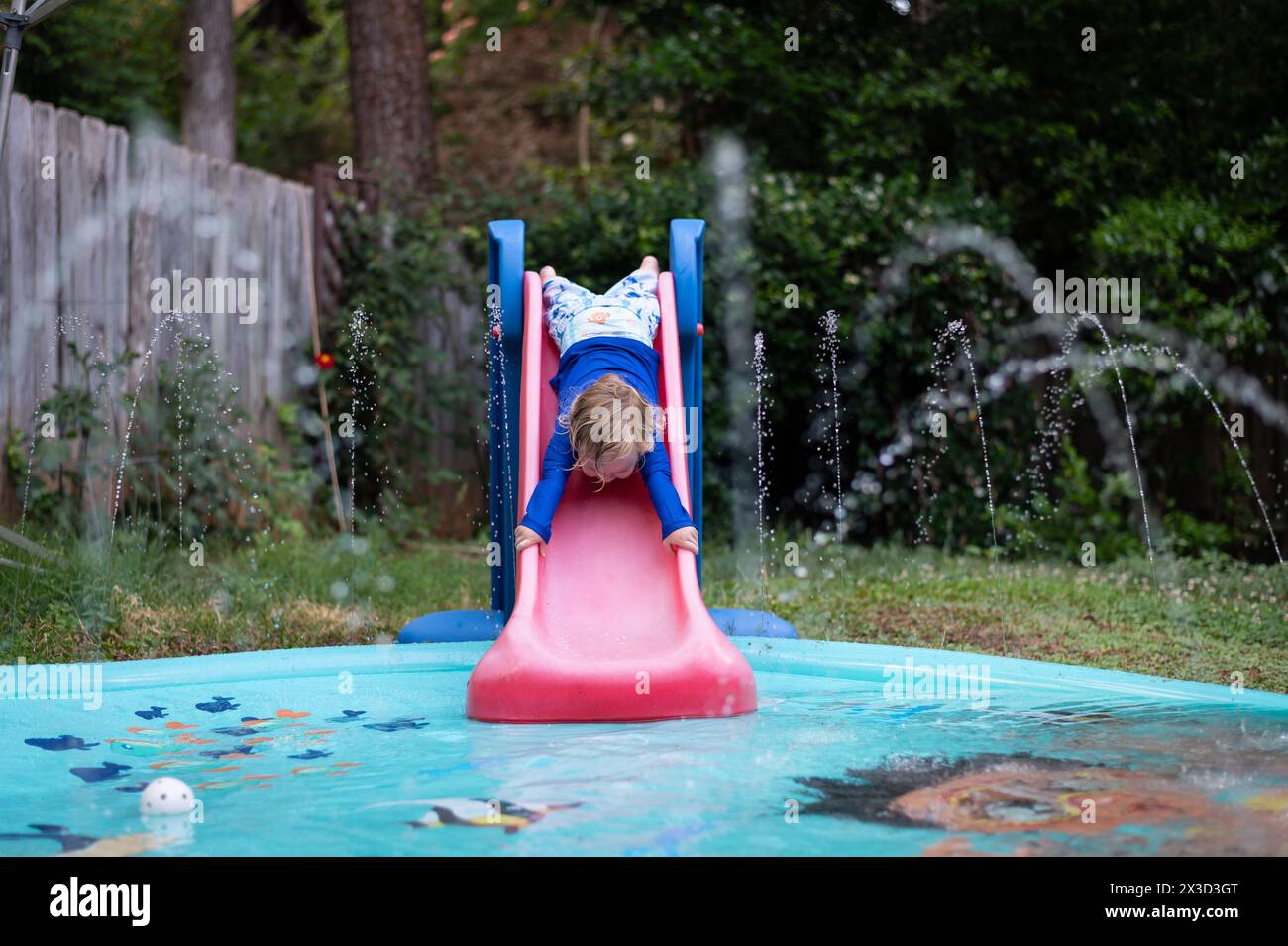 Young boy slides headfirst down toddler slide into splah pad Stock ...