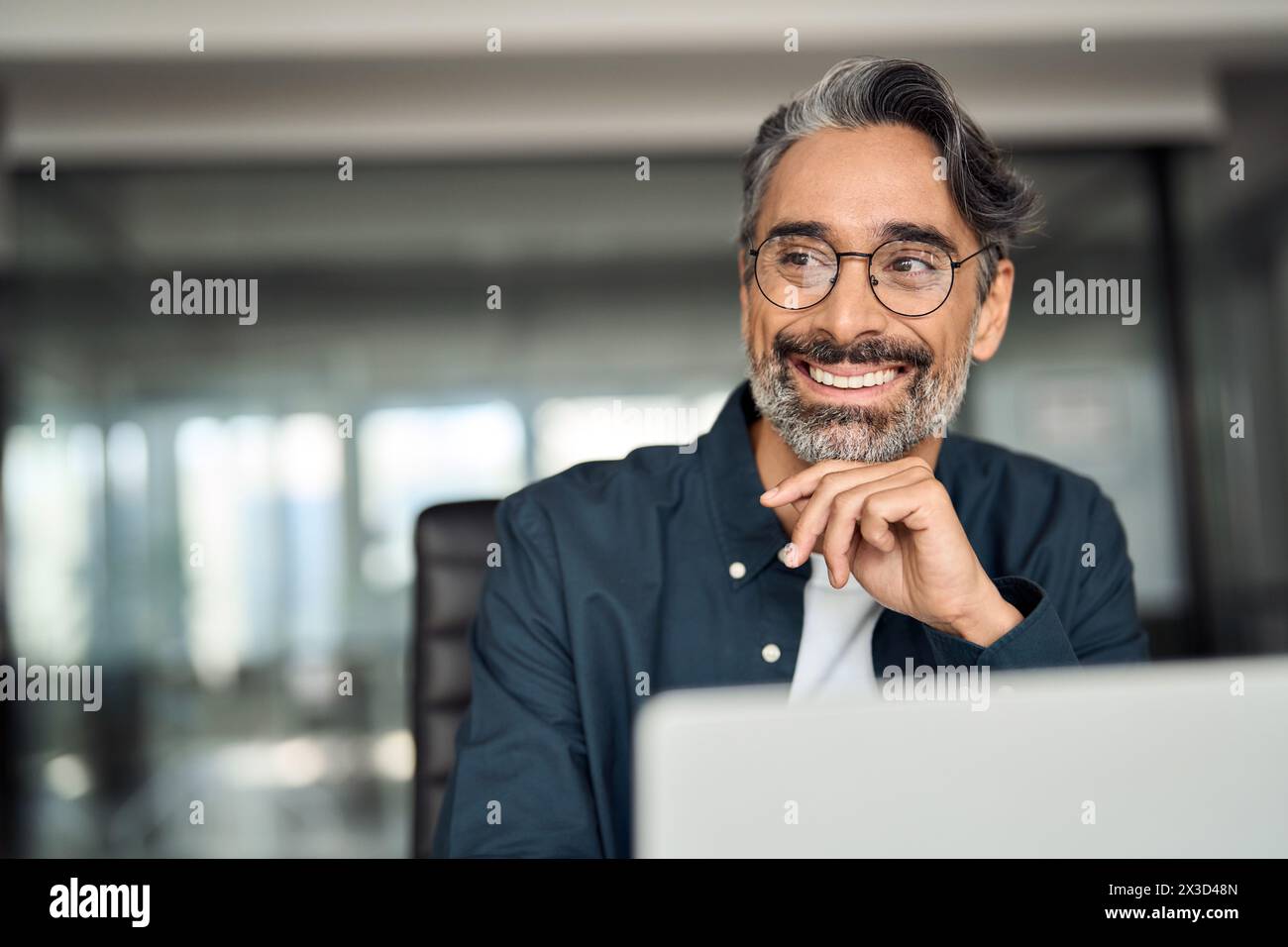 Happy middle aged business man sitting in office using laptop looking away Stock Photo - Alamy