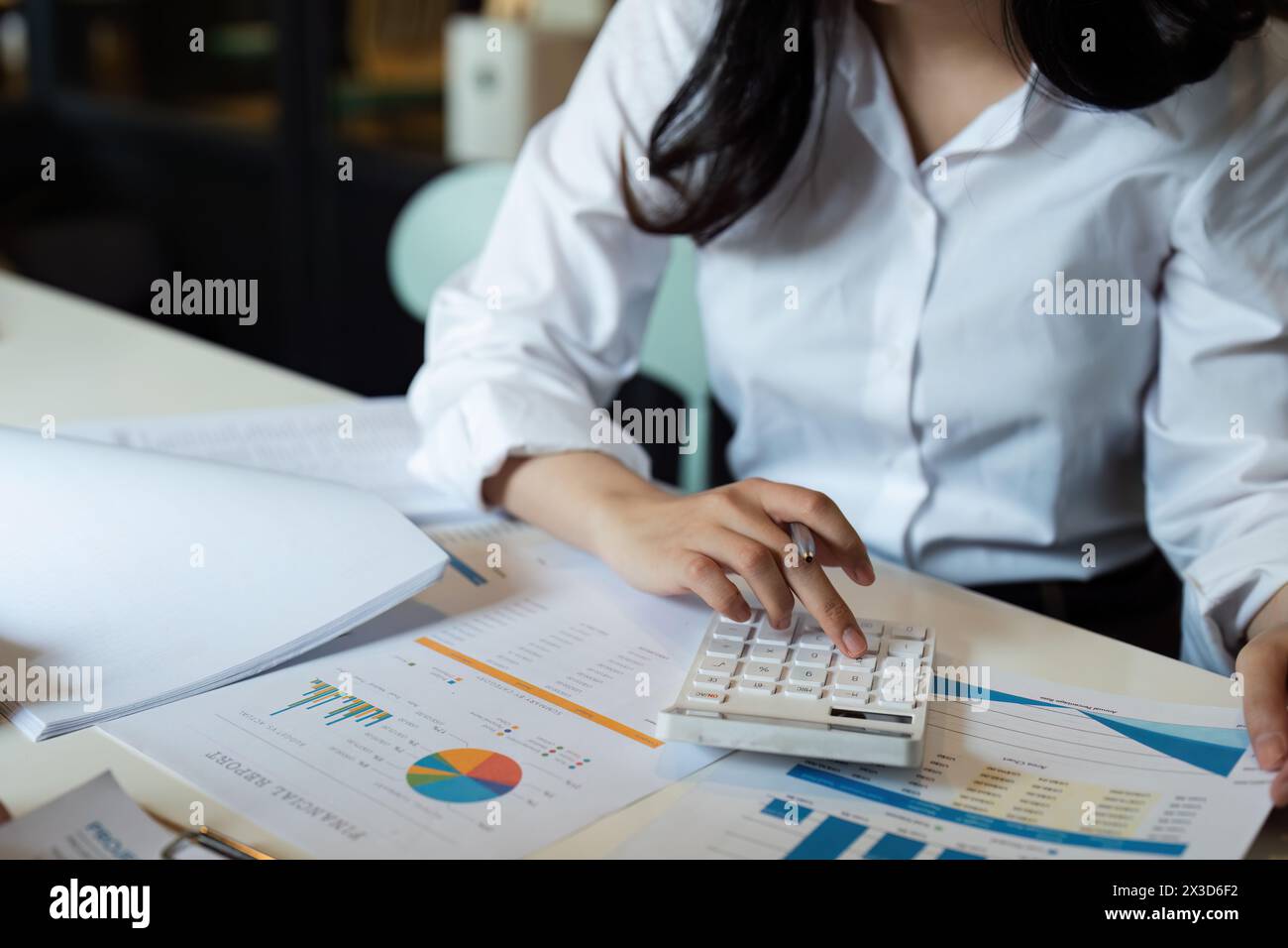 Businesswoman using a calculator to calculate numbers on a company's ...