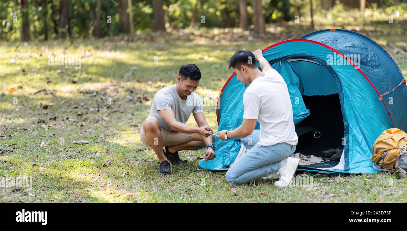 LGBTQIA Gay couple camping together in woods for holidays and helping ...