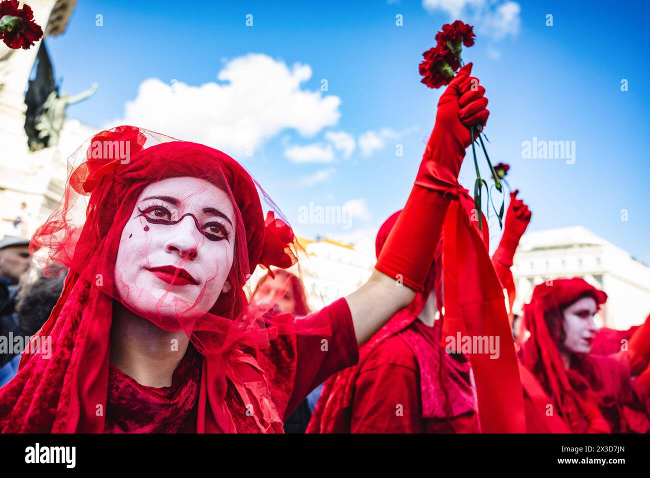 A member of Extinction Rebellion, dressed in red, holds a carnation ...