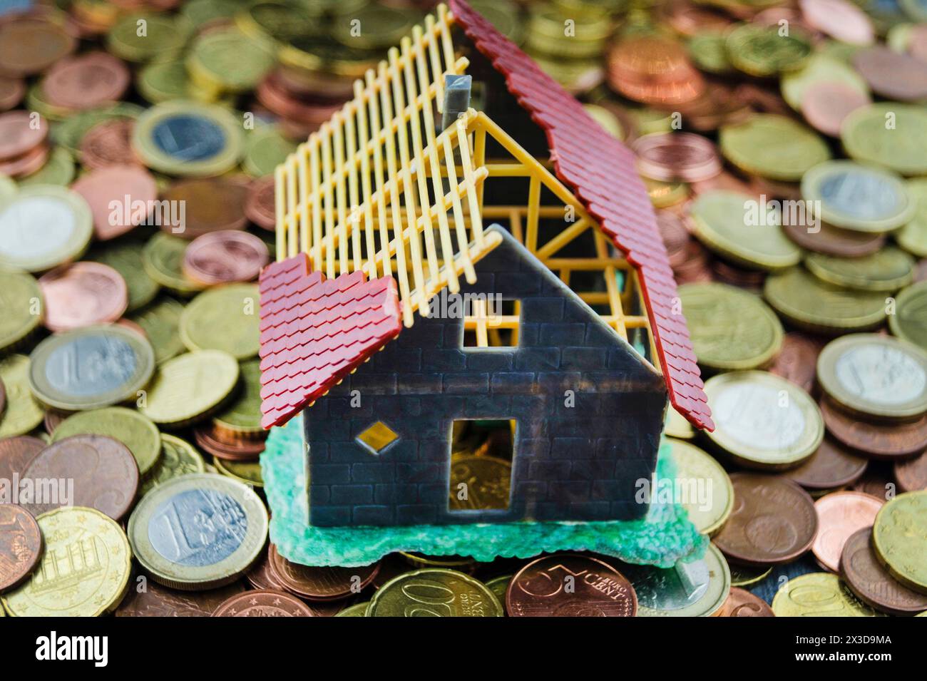 unfinished model house on Euro coins, symbolising the rise in house ...