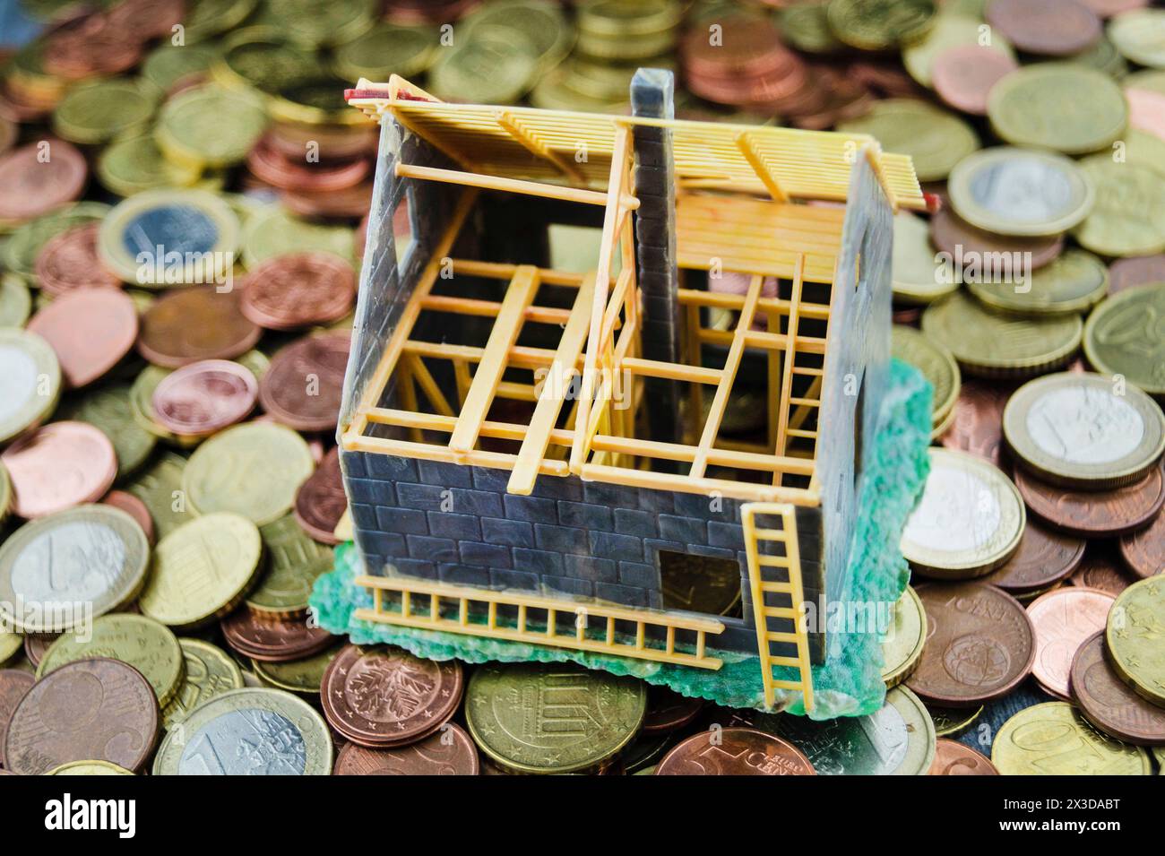 unfinished model house on Euro coins, symbolising the rise in house ...