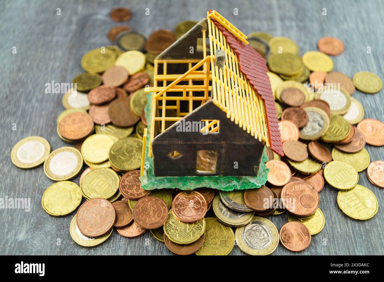 unfinished model house on Euro coins, symbolising the rise in house ...