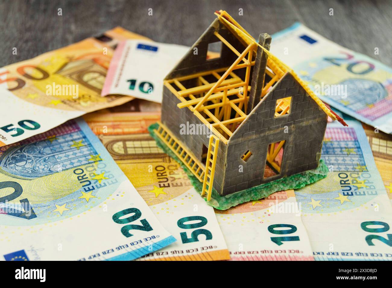 unfinished model house on Euro coins, symbolising the rise in house ...
