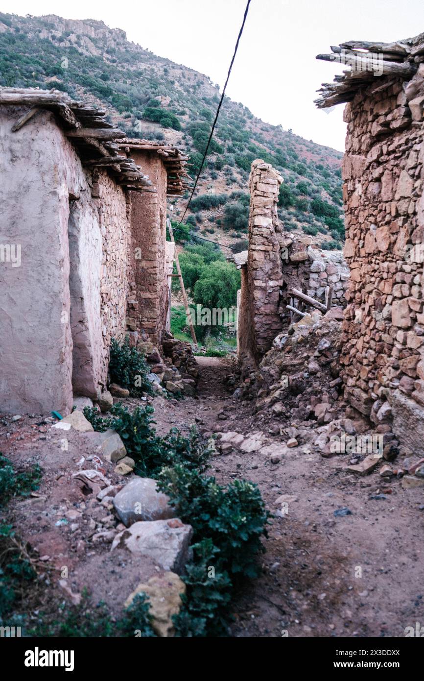 a road running between two stone buildings in a village surrounded by ...