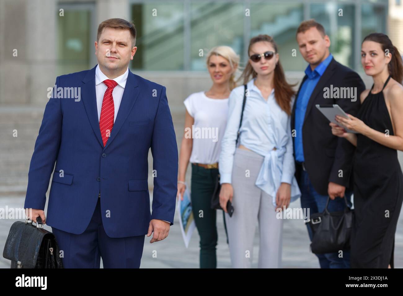 well dressed business team leader and four co-workers in background ...