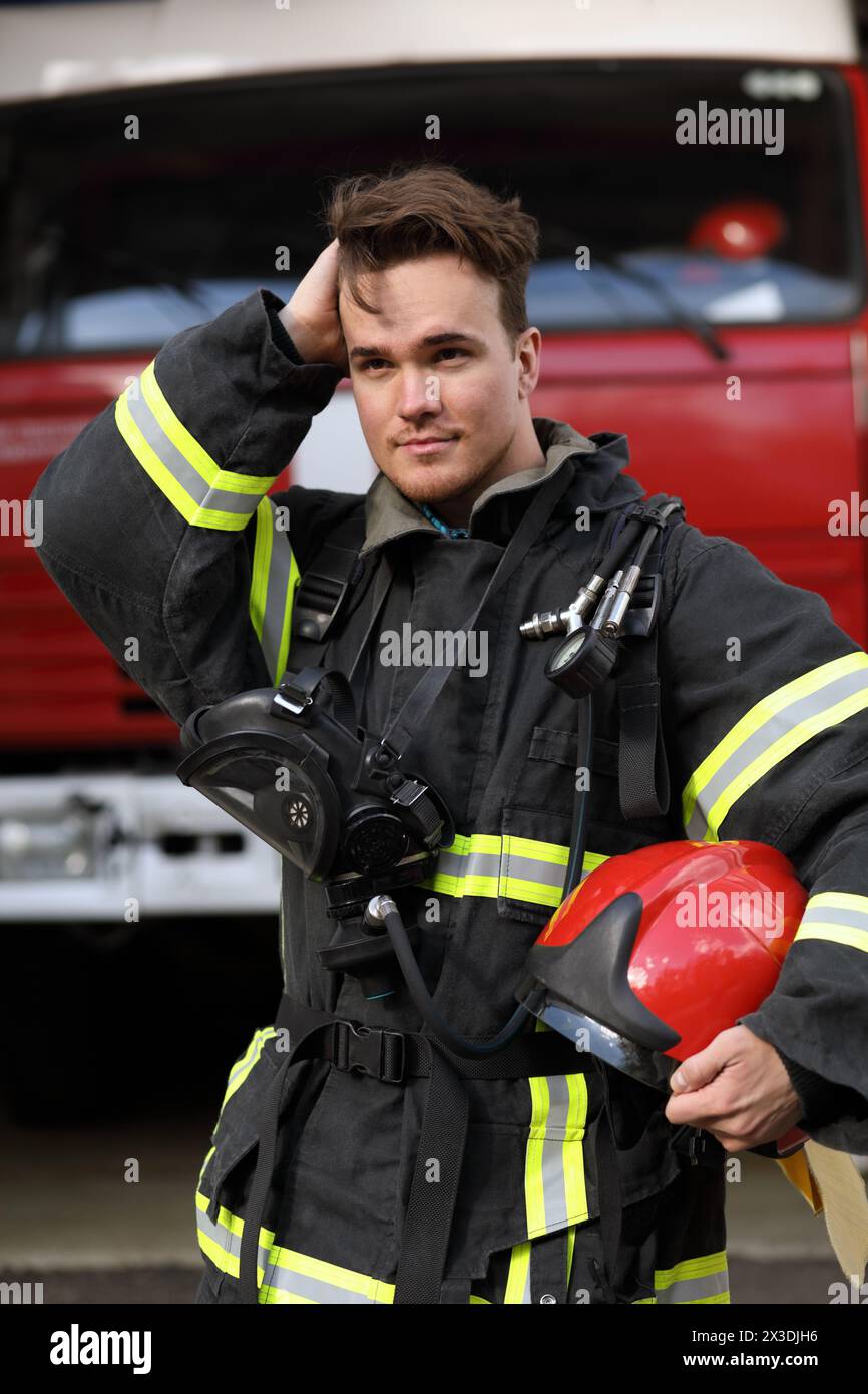 Portrait of fireman wearing fire fighter turnouts, adjusts hair with ...