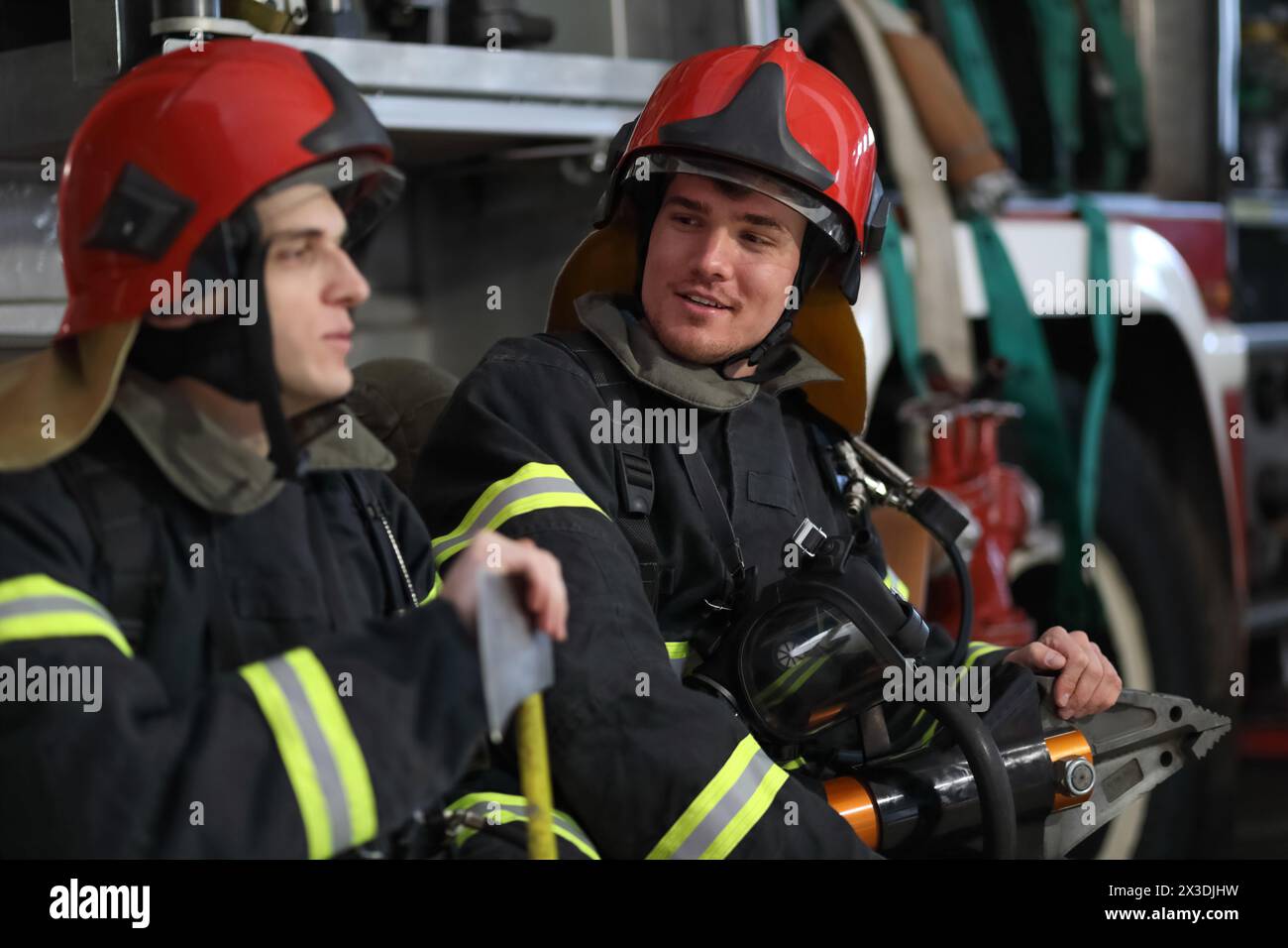 Two firefighters in protective suits and red fire helmet to protect ...
