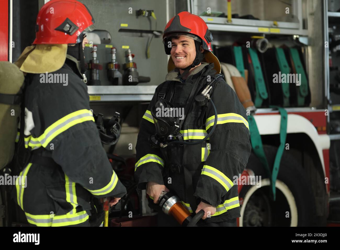 Two firefighters in protective clothing in helmets communicate with ...