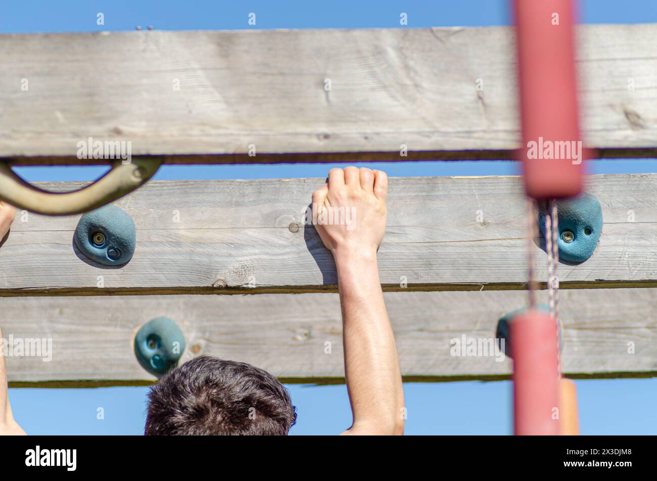 Detail of an athlete hanging from an obstacle at an obstacle course ...