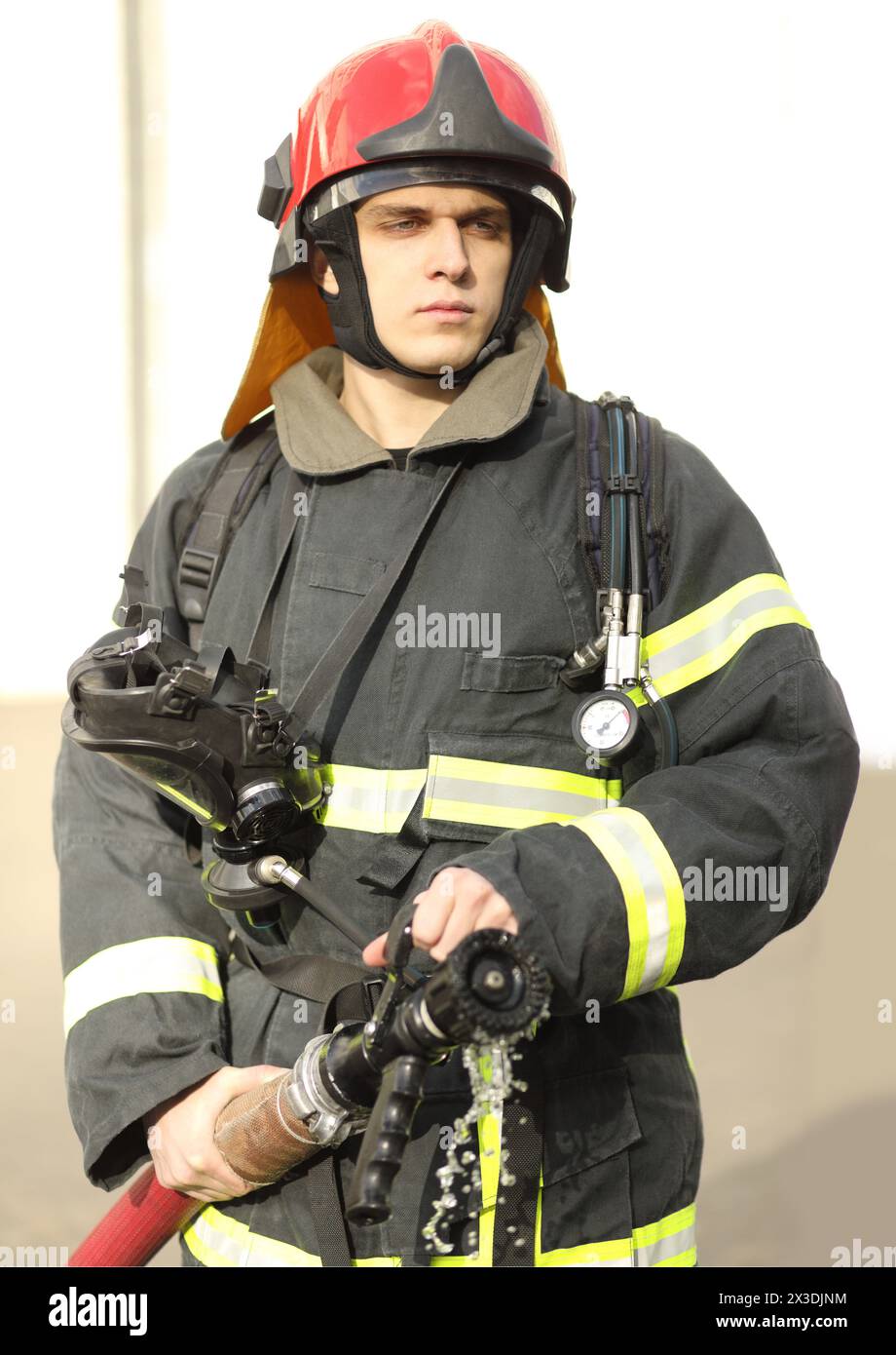 half-height portrait of fireman holds and adjust nozzle and fire hose ...
