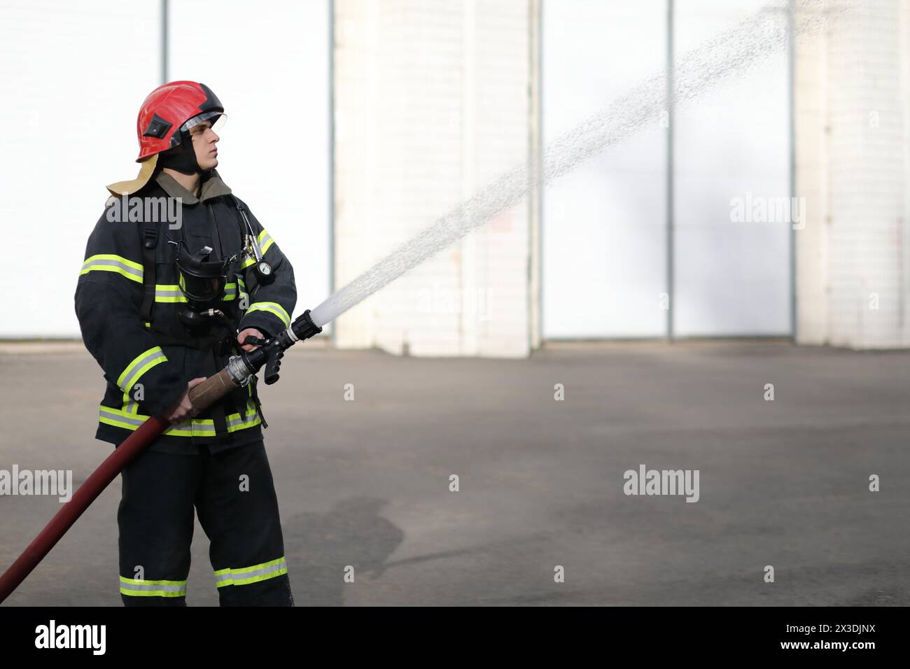 fireman holds and adjust nozzle and fire hose spraying high pressure ...