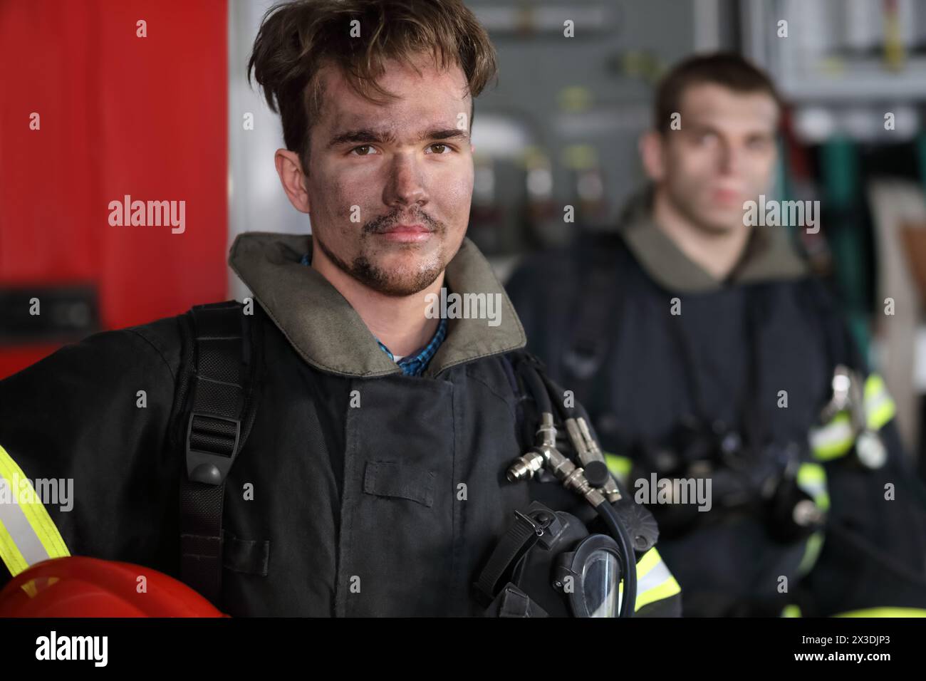 Two firefighters in protective suits with tool in hand without helmet ...