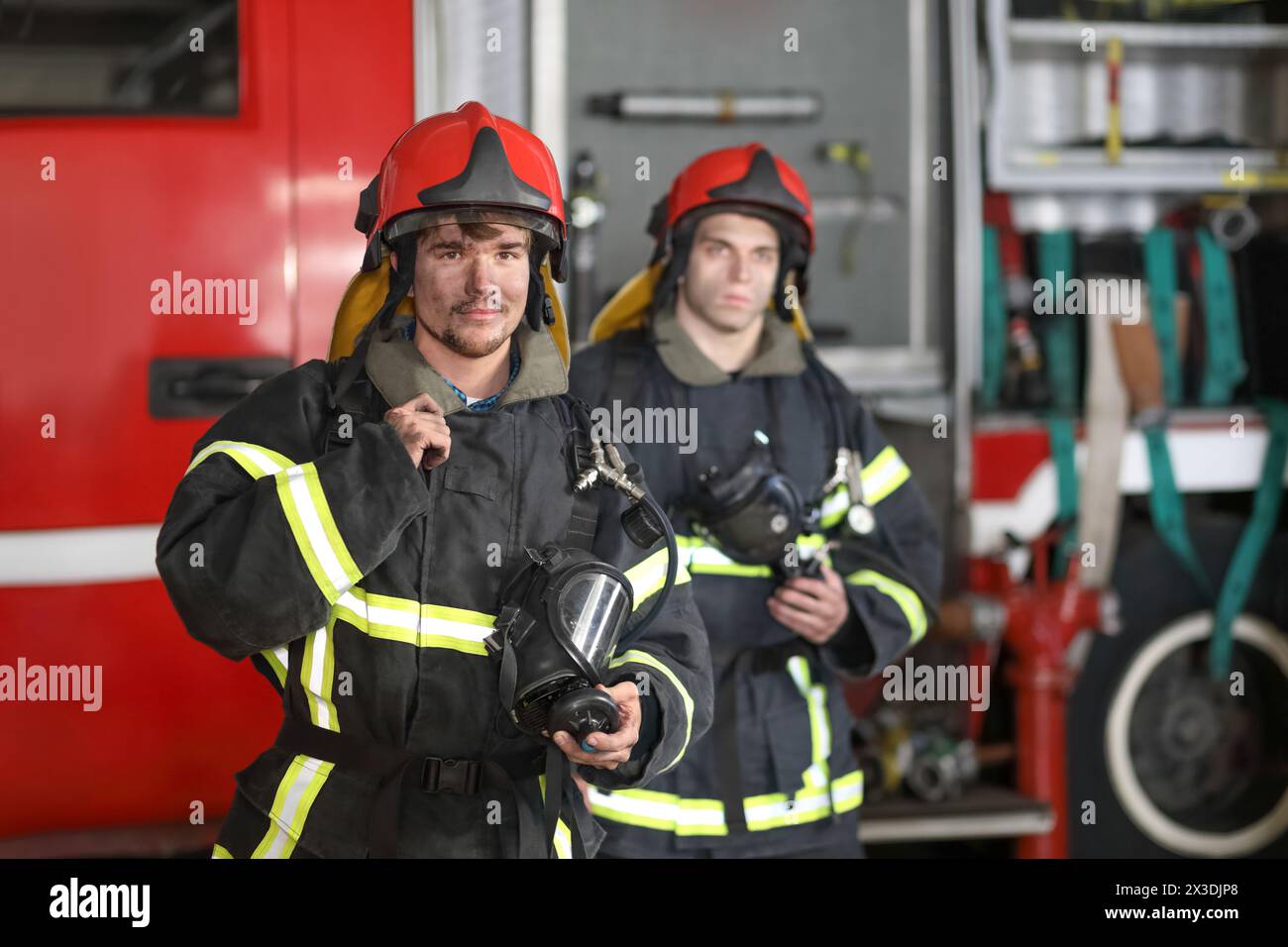 Two firefighters in protective suits and red fire helmet to protect ...