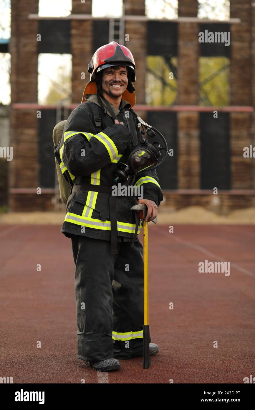 Portrait of smiling fireman wearing fire fighter turnouts, red helmet ...