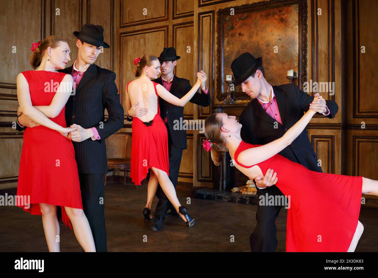 Handsome girl and man in hat dancing tango in retro room with fireplace ...