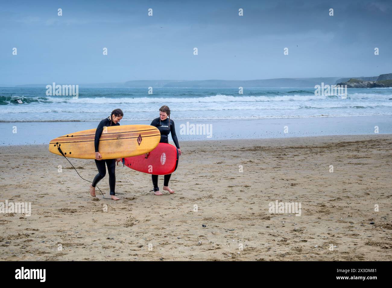Female surfers carrying their surfboards and walking out of the sea at ...
